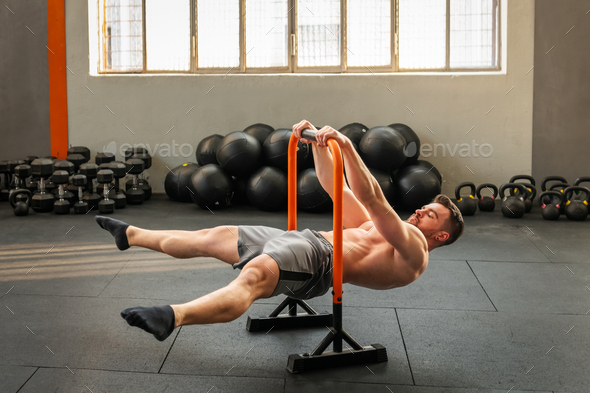 Muscular man performing straddle front lever calisthenics exercise ...