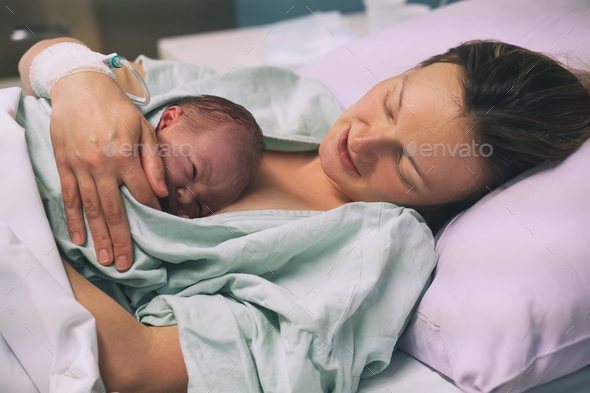 Mother and newborn. Child birth in maternity hospital. Woman giving ...