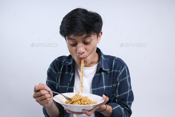 Excited Young Asian Man Eating Spicy Noodles Stock Photo by Queenmoonlite35