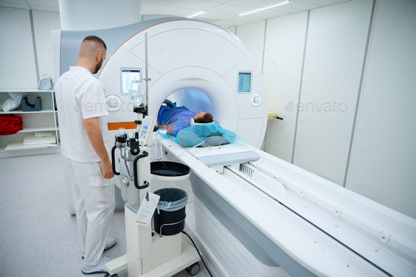 Doctor preparing man for knee magnetic resonance imaging procedure ...