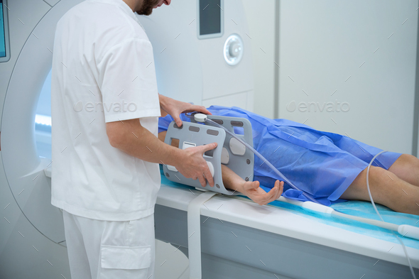 Radiographer preparing client for magnetic resonance imaging of lower ...