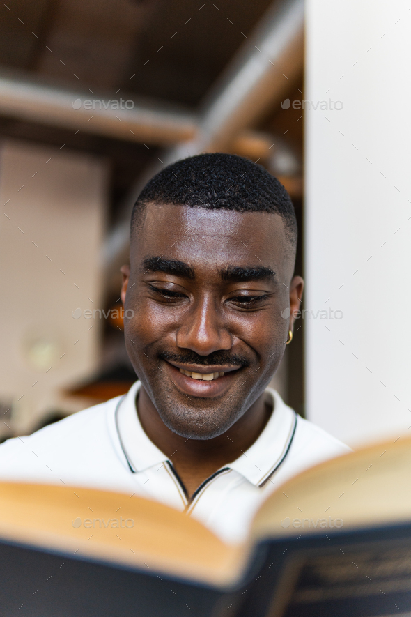 African American male reading book in cafeteria Stock Photo by ...