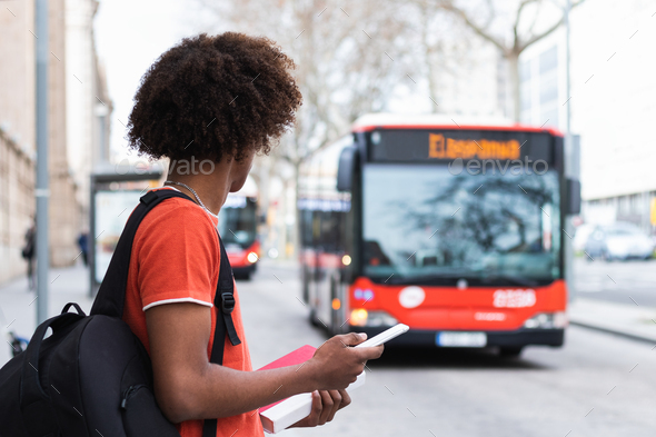 Anonymous black male student waiting for bus on street Stock Photo by ...