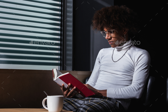 Relaxed young black man reading book in street cafe Stock Photo by ...