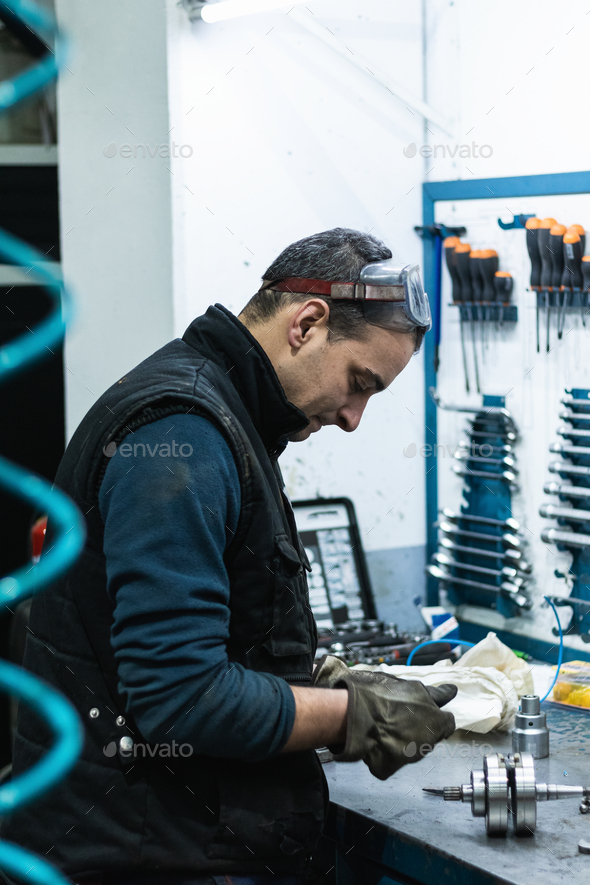 Professional mechanic using spanner while assembling vehicle engine ...