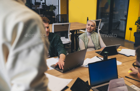 Positive team members talking on project in office Stock Photo by GaudiLab