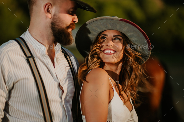 Portrait of young affectionate smiling rancher couple hugging at ranch ...
