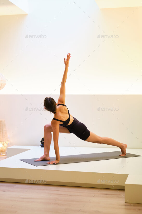 A woman backwards is doing Lunge With Spinal Twist yoga pose on a mat ...