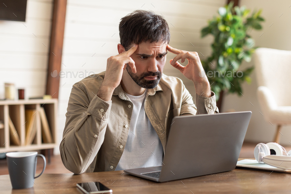 Concerned Man Frowning While Working on Laptop in Home Office Stock ...