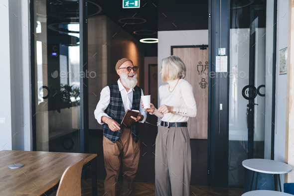 Cheerful senior colleagues sharing ideas in office Stock Photo by GaudiLab