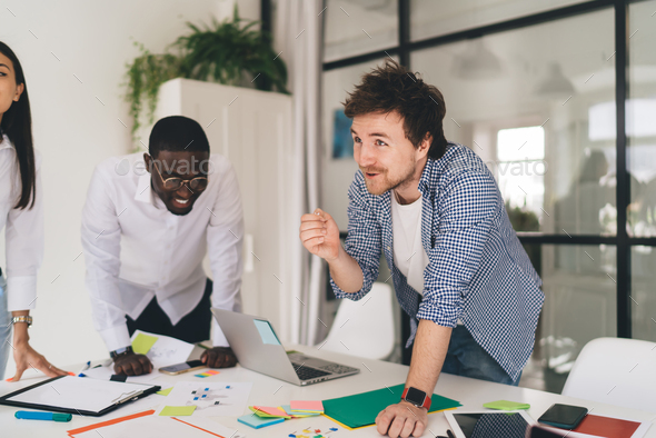 Ethnic man explaining point of view while diverse colleagues laughing ...