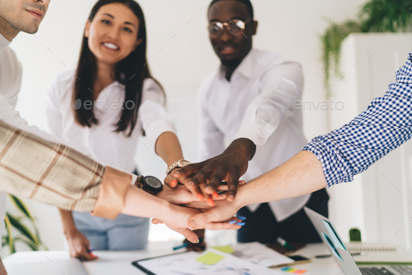 Colleagues demonstrating unity with gathering hands gesture during ...