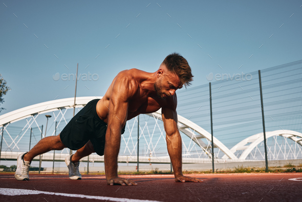 Shirtless handsome man doing push-ups on the basketball court outside ...