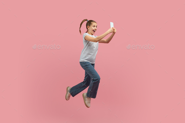 Girl Jumping in the Air With Cell Phone Stock Photo by Prostock-studio