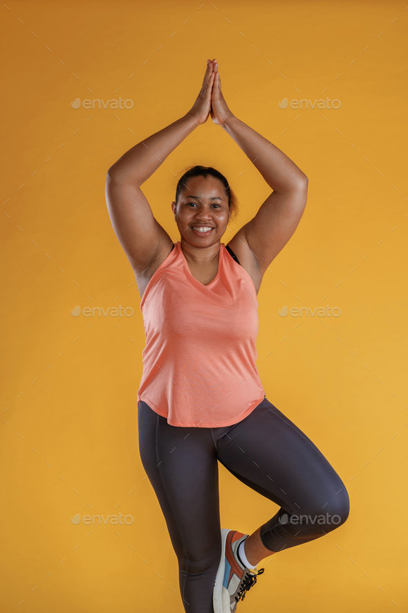 Yoga stance, with hands up. African American woman is in the studio ...