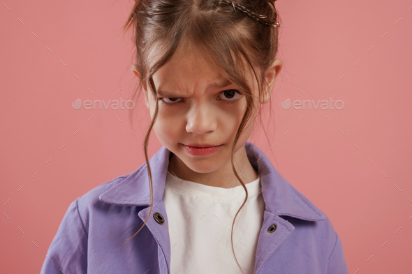 Suspicious facial expression. Cute little girl is against pink ...