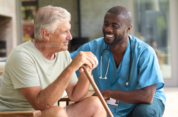 Male Nurse Visiting Senior Man Using Walking Stick With Mobility Issues ...
