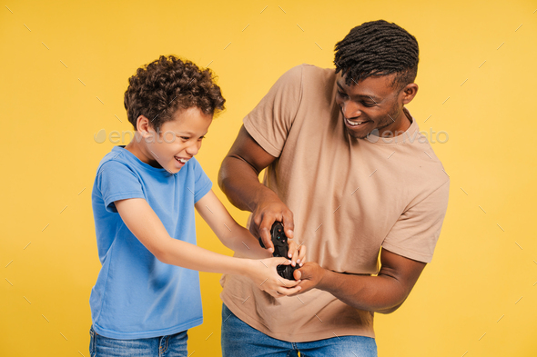 Excited, smiling African American boy and his dad together playing ...