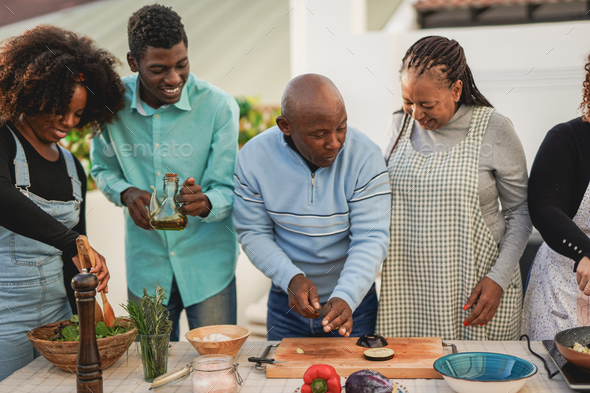 Happy african family cooking together healthy dinner at house patio ...