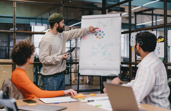 Man explaining project to colleagues with charts and diagrams on board ...