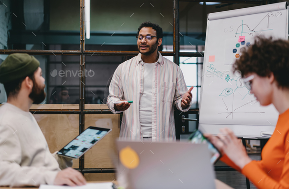 Cheerful man presenting project to colleagues while working in office ...
