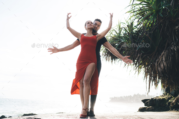 Positive couple professional dancers with stretched hands up and down ...