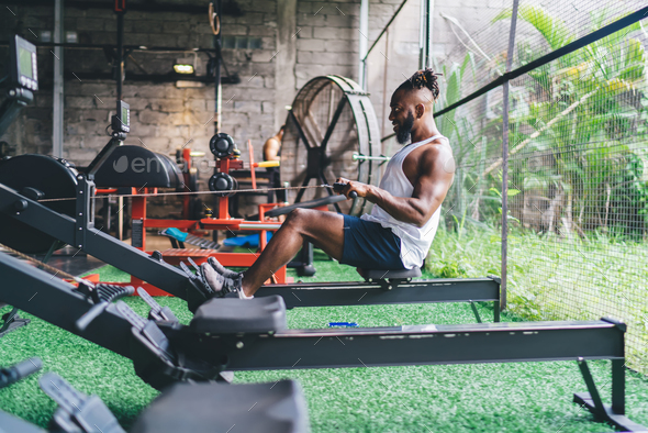 Strong male athlete pulling cable while doing exercise on bench Stock ...