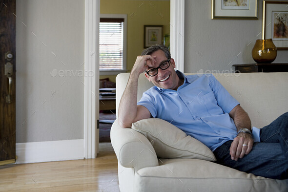 Man lounging comfortably on a sofa at home with a happy smile. Stock ...