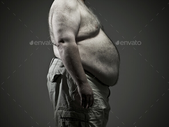 Side view of a shirtless overweight man standing against a grey ...