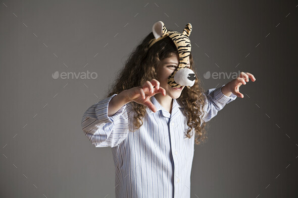 Child playfully roaring while wearing a tiger mask Stock Photo by Image ...