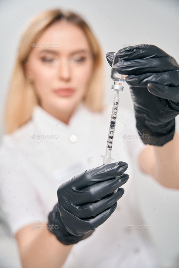 Focus of syringe with beauty injection in hands of blurred female ...