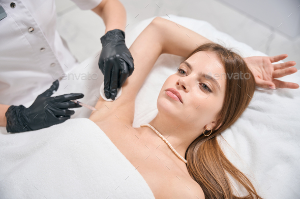 Partial female beautician doing armpit beauty injection with syringe of ...