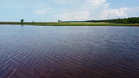 Aerial flyover above a tranquil lake Pape (Latvia) surface in calm ...