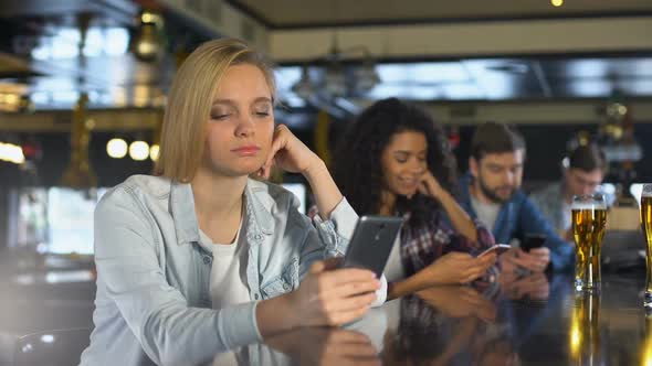 Young People Bored in Bar, Using Phones Instead of Live Communication ...