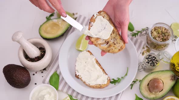 Woman Standing at Kitchen Spreading Whizzed Cream Cheese on Slice of ...