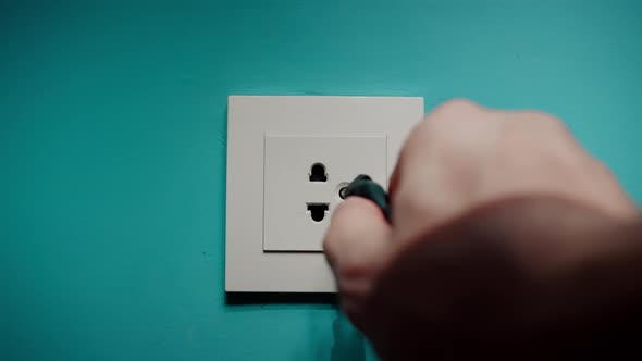 Man Inserts Plug Into Electrical Socket On A Blue Wall, Stock Footage