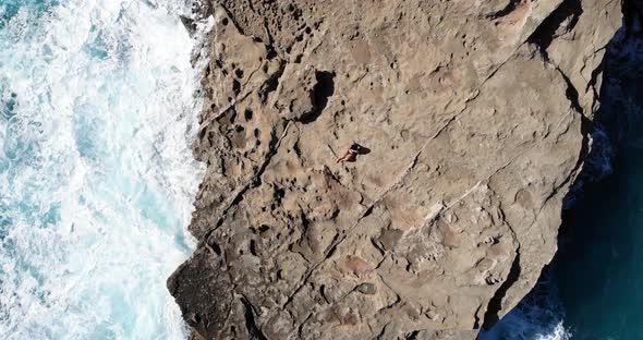Aerial, top down, drone shot of a woman laying on a cliff, Stock Footage