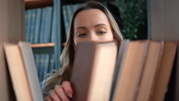 Pensive Blonde Woman Choosing Book for Reading Searching Information ...