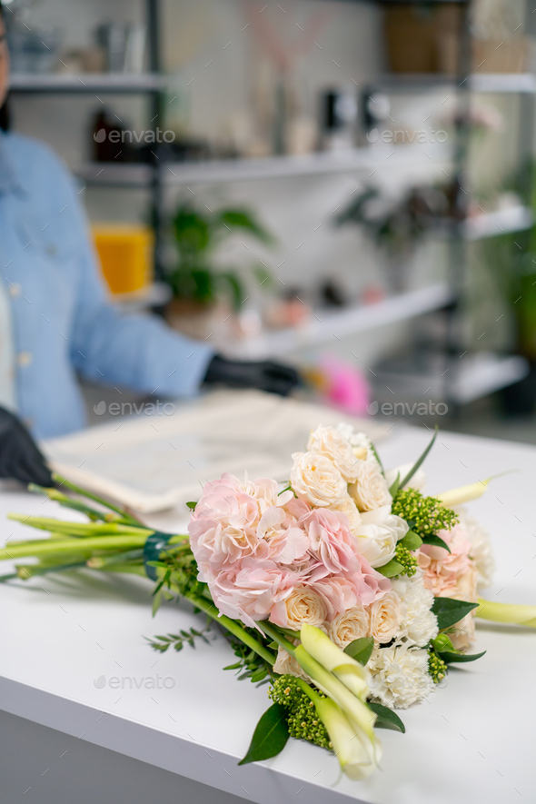 in a flower shop florist prepares a white paper wrapper for decorating ...
