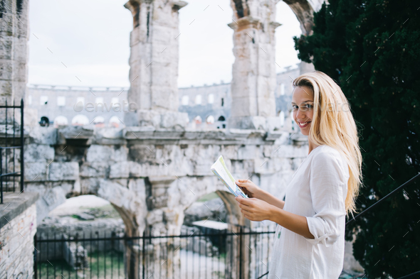 positive woman 20s traveler using map for searching locations in ...