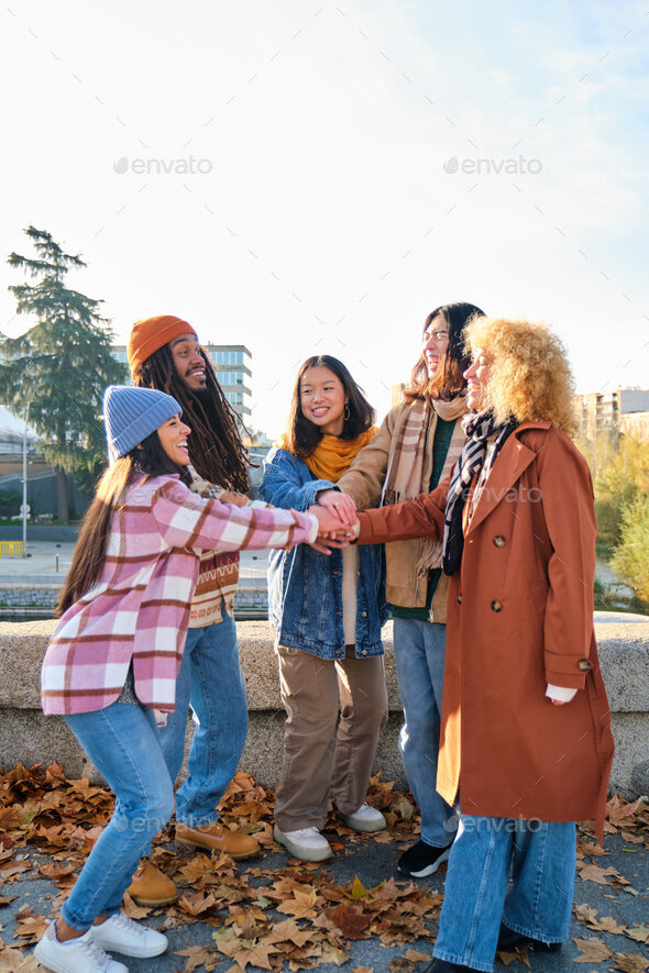 Happy diverse group of friends holding hands stacking them together ...