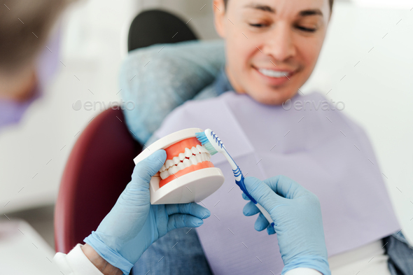 Dentist doctor holding jaw and showing patient, attractive young man ...