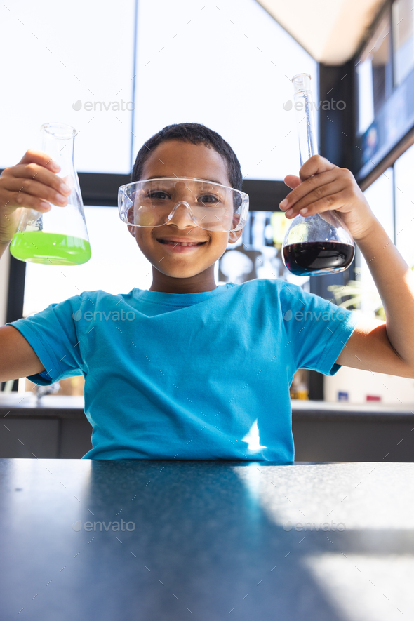 Biracial boy conducts a science experiment at school in the classroom ...