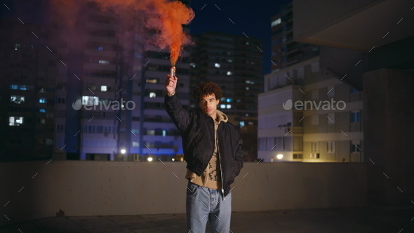 Man holding colorful flare at night cityscape framing urgent signal ...
