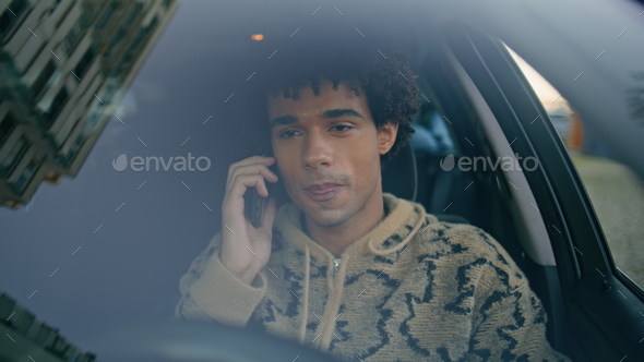 Smiling zoomer talking cell phone in automobile closeup. Latin american ...