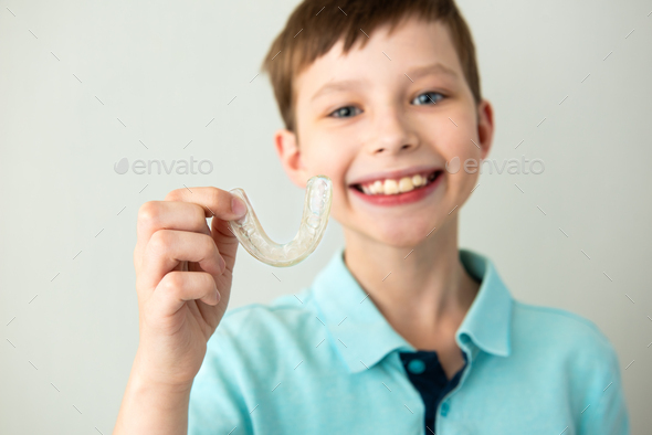 Child boy hold in hand invisible transparent aligners, invisalign ...