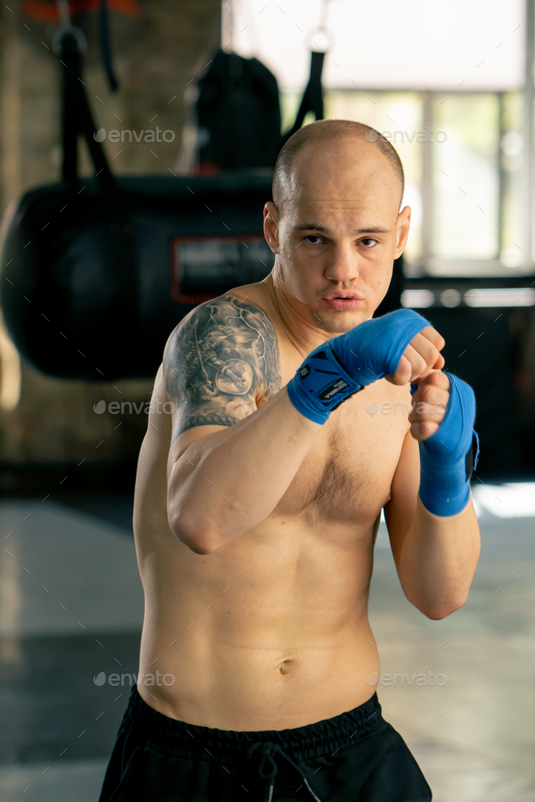 close-up in a boxing fight club bald young boxer with tattoos in blue ...