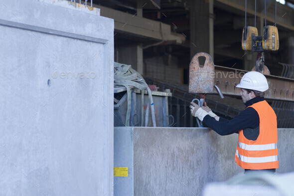 Factory worker attaching rope to concrete block in concrete ...