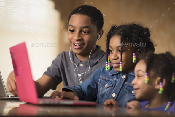 Teenage boy and sisters at dining table typing on laptop Stock Photo by ...