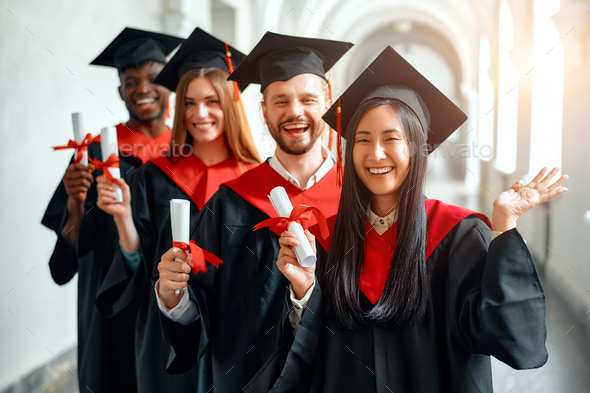 Graduates celebrating academic achievement with diplomas at university ...